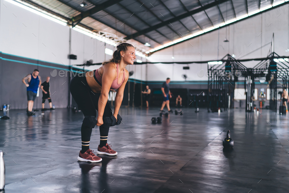 Happy female bodybuilder in sportive tracksuit smiling pursuit practice ...