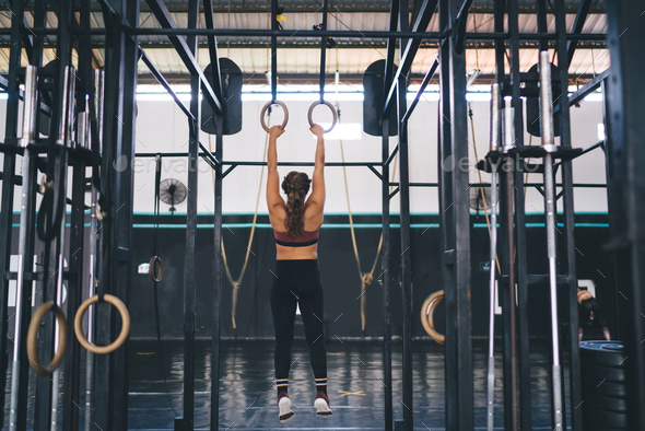 Back view of determined bodybuilder training with sportive equipment ...