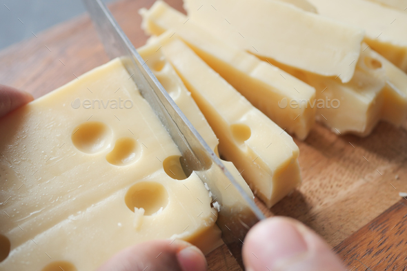cutting cheese with knife on a chopping board on table Stock Photo by ...