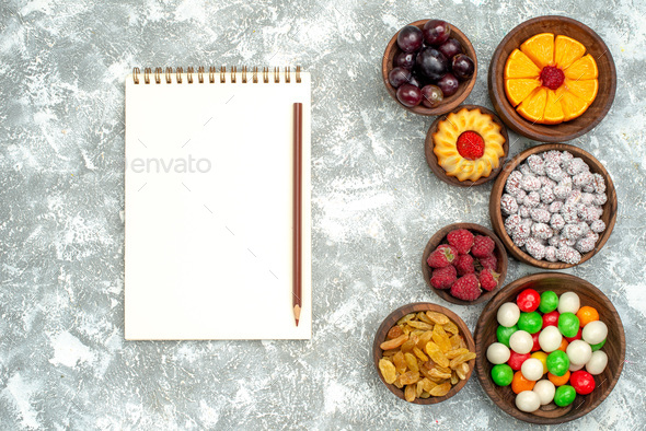 top view different candies with raisins and fruits on a white ...