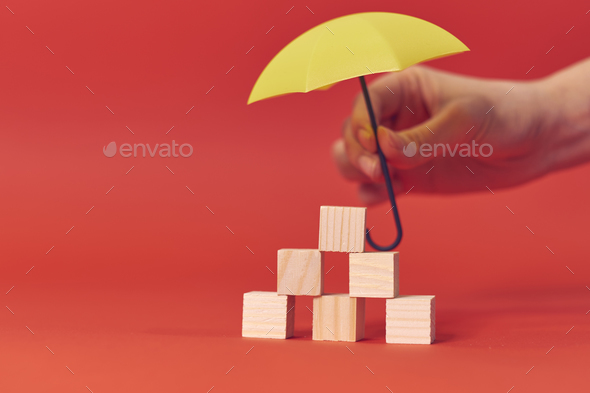 wooden blocks under umbrella on table against red background Stock ...