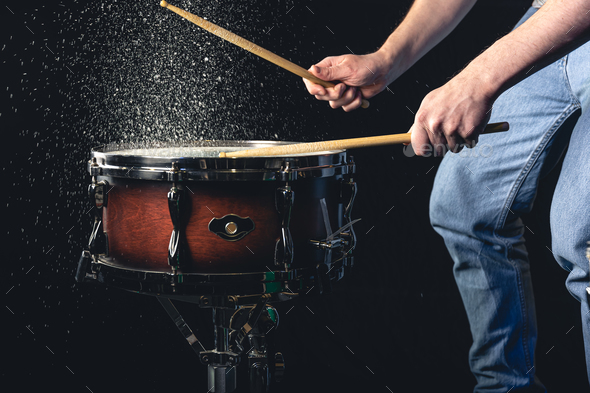 Drummer using drum sticks hitting snare drum with splashing water ...