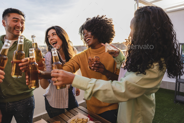 group of friends partying with beer on rooftop - multiracial women ...