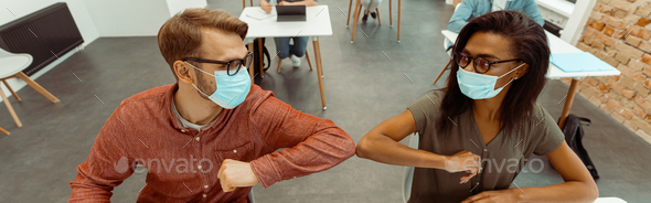 Two students greeting bumping elbows at workplace Stock Photo by ...