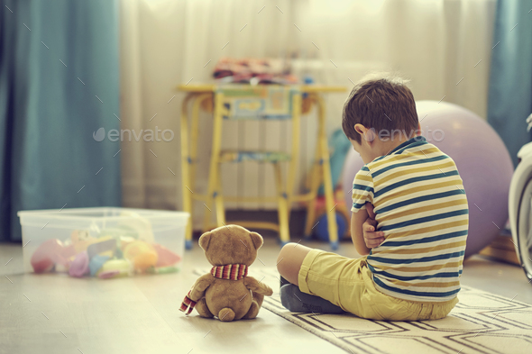 sad boy sits on the floor of the nursery. lonely kid misses home Stock ...