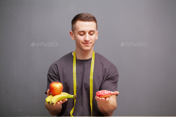 Shaped and healthy body man holding a fresh fruits and junk food Stock ...