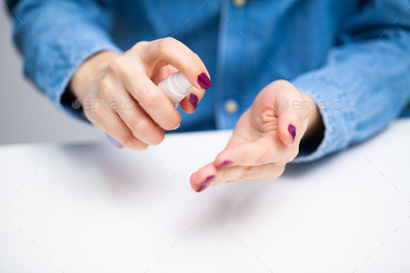 Woman in office uses antiseptic for disinfection. Stock Photo by maksymiv