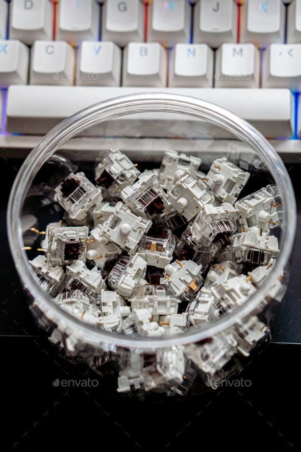 Vertical closeup of mechanical keyboard switches piled in a transparent ...