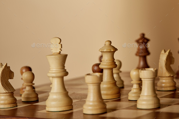 selective focus of chess pieces on brown chess board and beige ...