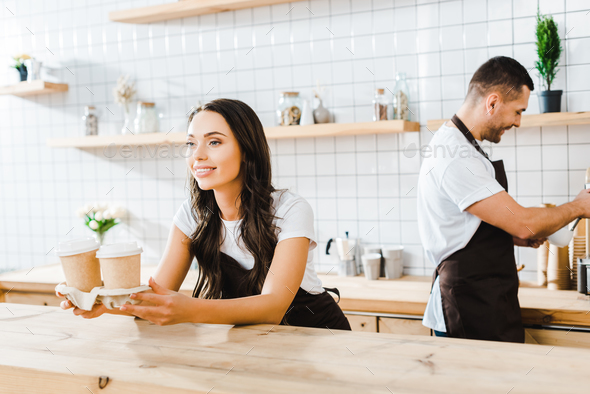 attractive brunette cashier standing behind bar counter and holding ...