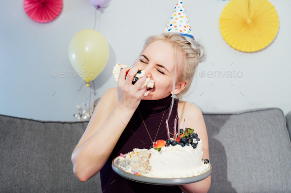Woman eating birthday cake with her hands, her face stained cream ...