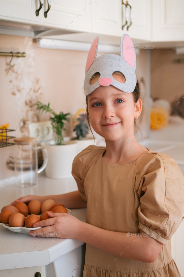Cute little girl wearing rabbit mask holding plate with eggs. Easter ...