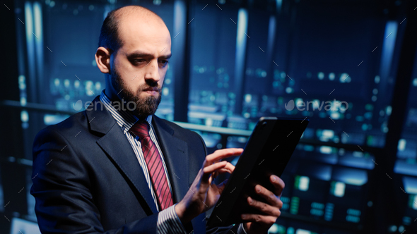 Male database admin checking hosting server on tablet Stock Photo by DC_Studio