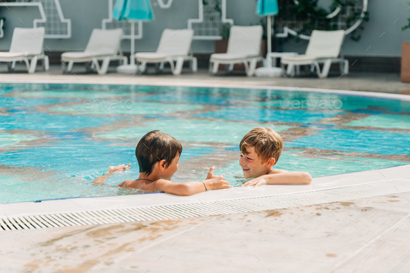 Two brothers Childs laughing while playing in swimming pool at sunny ...