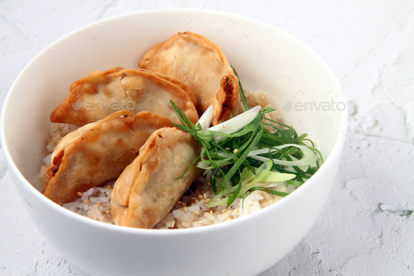 Freshly cooked fried rice topped with fried Gyoza Stock Photo by junpinzon
