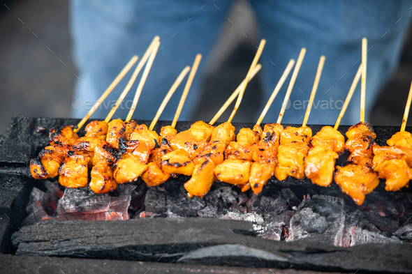 Closeup of chicken satay being barbecue with traditional pit and fired ...