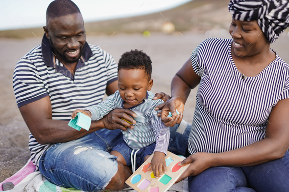 Happy african parents having playful time with toddler on the beach ...