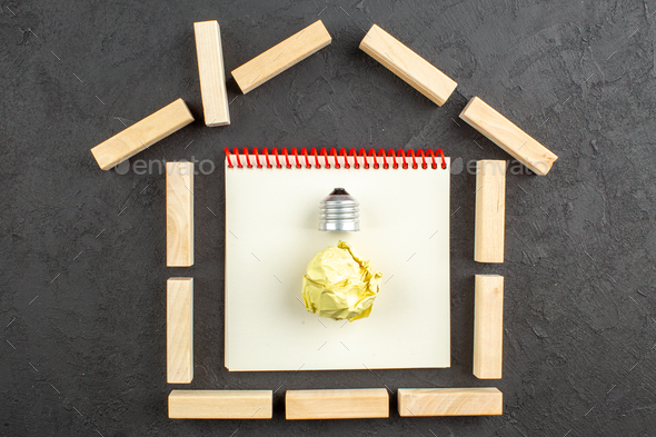 top view house shaped wood blocks idealight bulb on notepad on black ...
