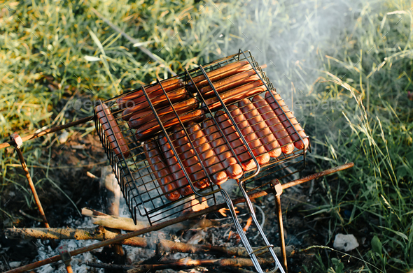 Cooking fried food on fire in nature. Top view hot sausages in grill ...