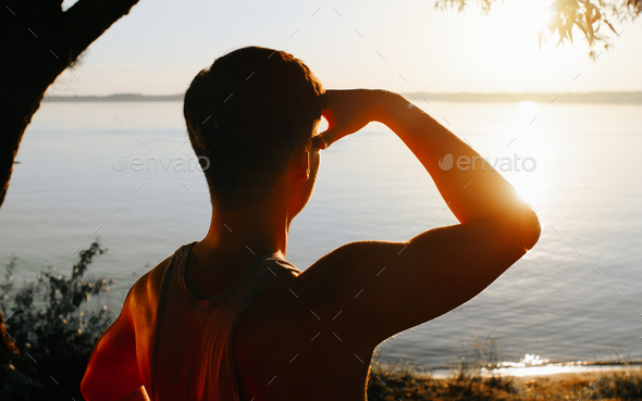 Back view of unrecognizable athletic man enjoying beautiful sunset at ...