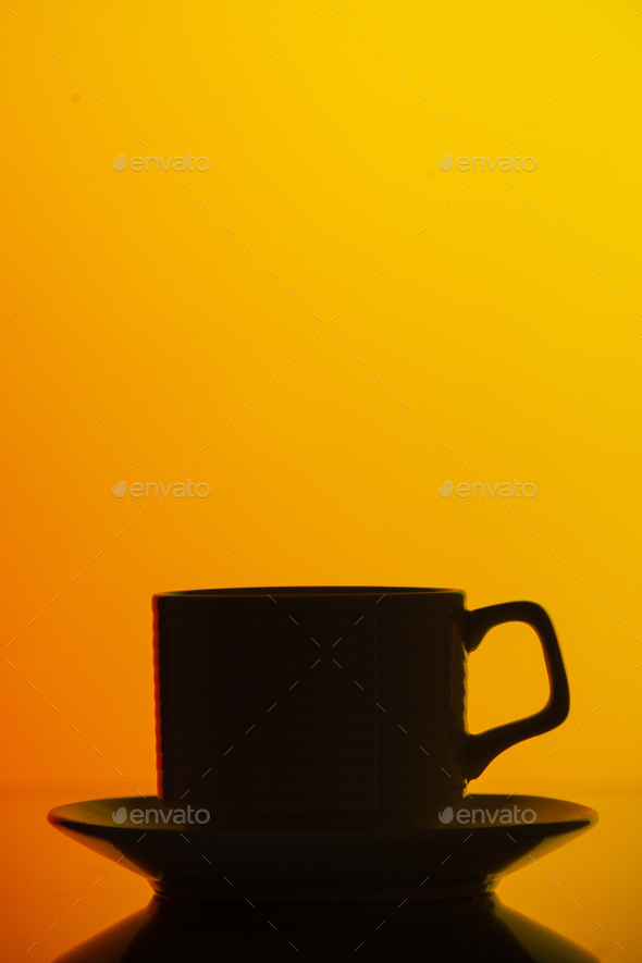 front view black tea cup in dark shadow on a yellow background color ...