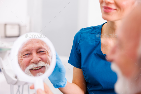 Patient looking in the mirror at dentist office smiling satisfied Stock ...