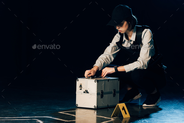 investigator in cap with investigation kit near chalk outline at crime ...