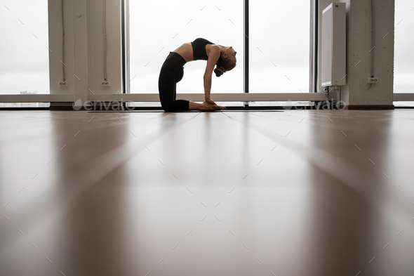 Fit female bending back on yoga mat at spacious studio Stock Photo by ...