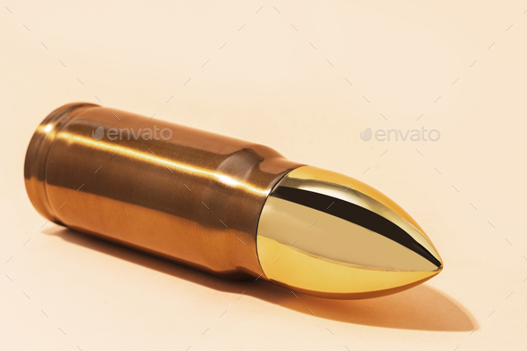 Big and shiny bullet against beige background Stock Photo by BLACKDAY