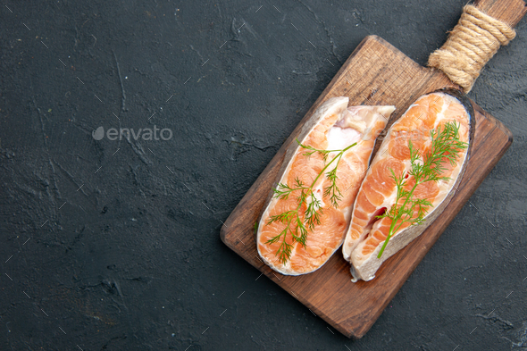 Horizontal view of salmon fish on brown wooden cutting board with green ...