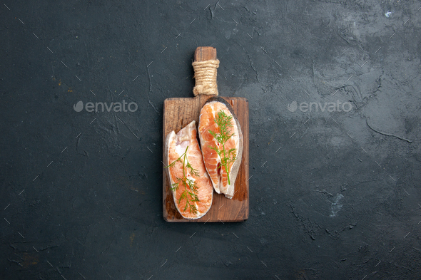 Horizontal view of salmon fish on wooden cutting board with green on ...