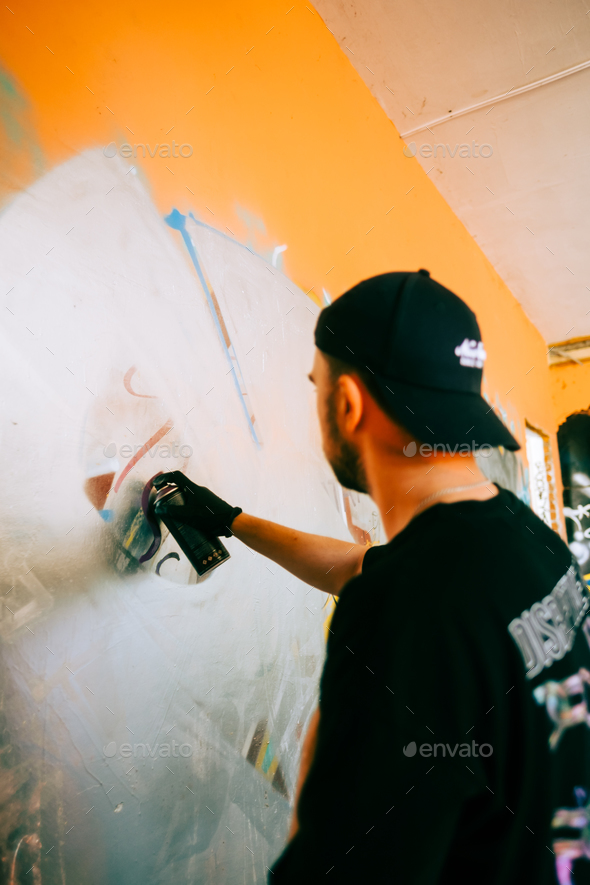 Young caucasian man graffiti artist drawing on a wall. Stock Photo by ...