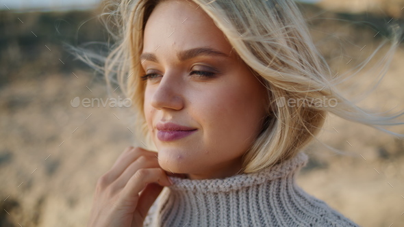 Sweater girl enjoying windy autumn portrait. Hair blowing in blond ...