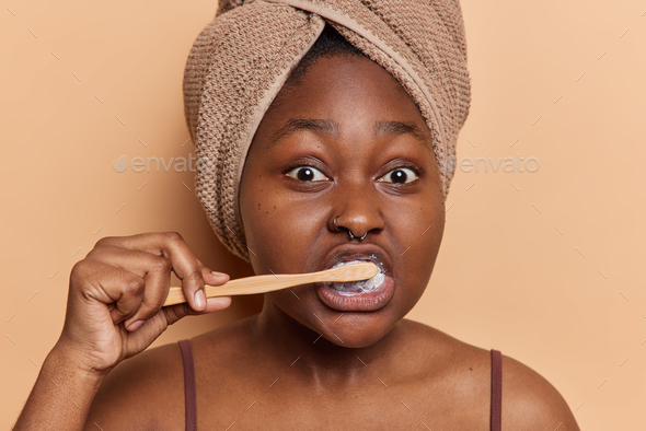 Dental hygiene. Dark skinned plump woman brushes teeth with toothpaste ...