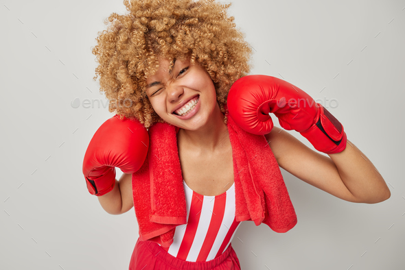 Positive female boxer with curly hair wears boxing gloves ready for ...