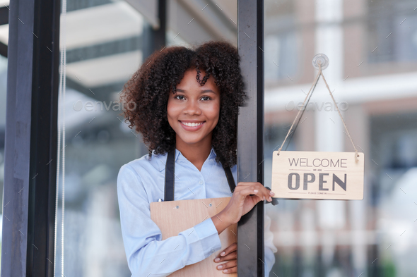 Female store owner or staff, food, cafe or bar, showing the OPEN sign ...