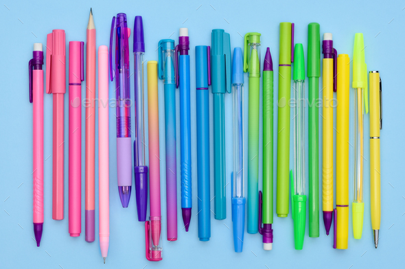 Rainbow stationery collection of pens and pencils on a light blue ...