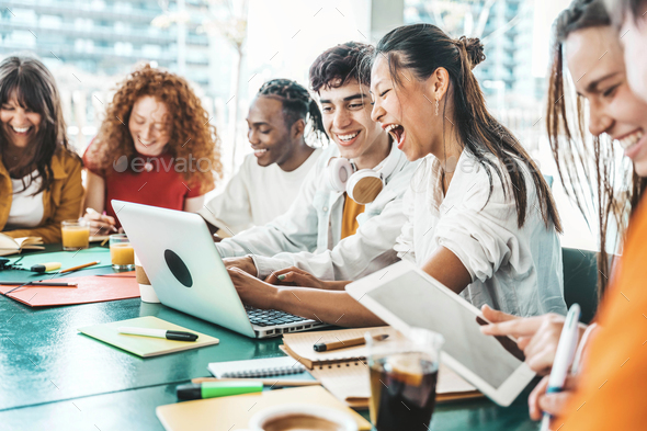 Multiracial university students sitting together at table with books ...