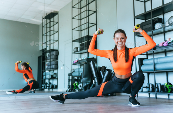 Fit hispanic young woman in orange sportswear stretches legs bends ...