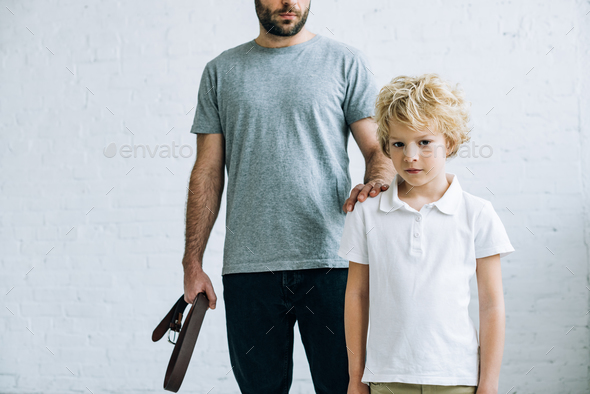 cropped view of father with belt and upset son at home Stock Photo by ...