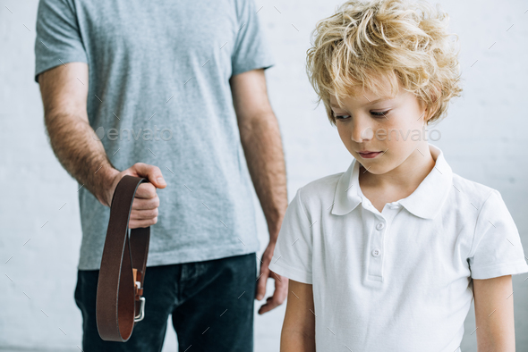 cropped view of father with belt and upset son at home Stock Photo by ...