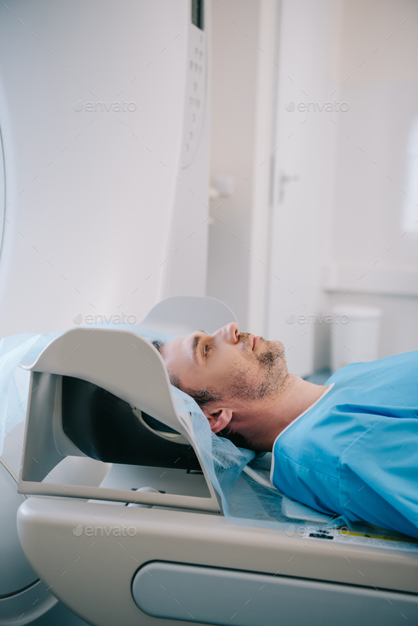 handsome man lying on ct scanner bed during tomography diagnostics in ...