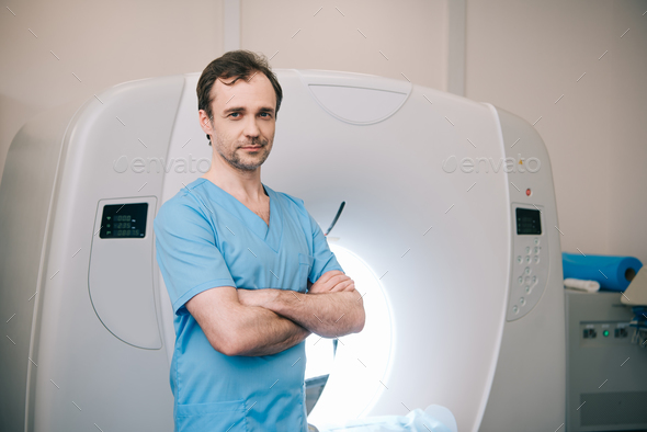 smiling radiologist standing near computed tomography scanner with ...