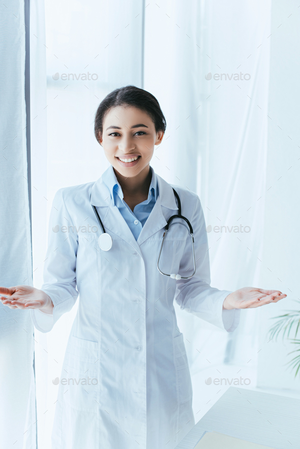cheerful latin doctor with stethoscope showing welcome gesture while ...