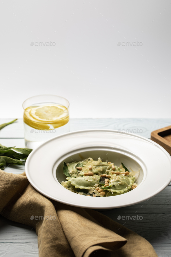 green ravioli with pine nuts and sage at wooden table with napkin and ...