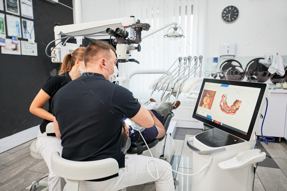 Dentist scanning patient's teeth with modern machine for intraoral ...
