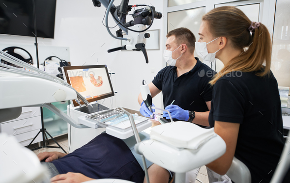 Dentist scanning patient's teeth with modern machine for intraoral ...