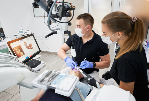 Dentist scanning patient's teeth with modern machine for intraoral ...