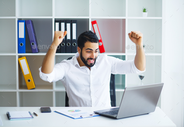 Excited young businessman celebrate victory cheerful in modern office ...