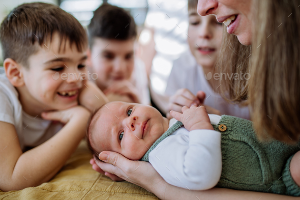 Mother and her sons cuddling their newborn baby. Stock Photo by halfpoint